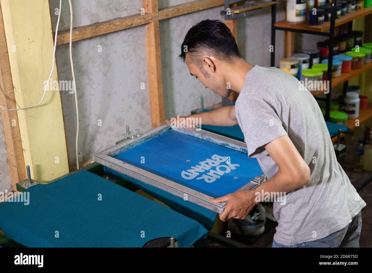 male worker sets up carefully and install the silkscreen frame on the ...