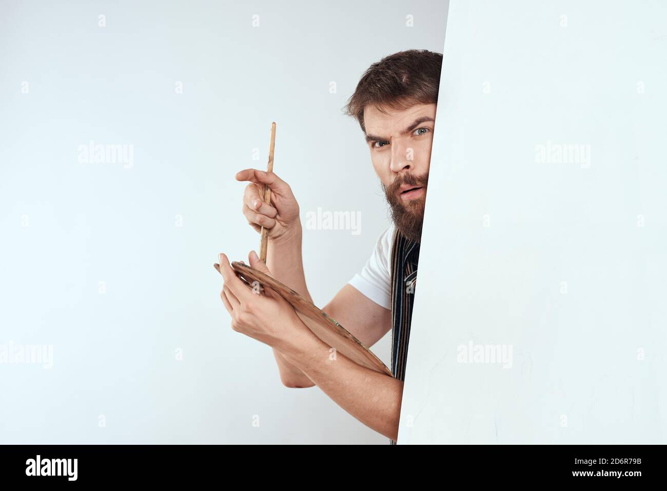 Male artist hiding behind an easel palette drawing art Stock Photo - Alamy