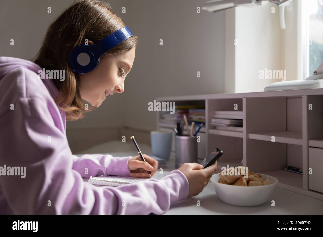 Smiling teen girl in headphones study at home using cellphone Stock ...