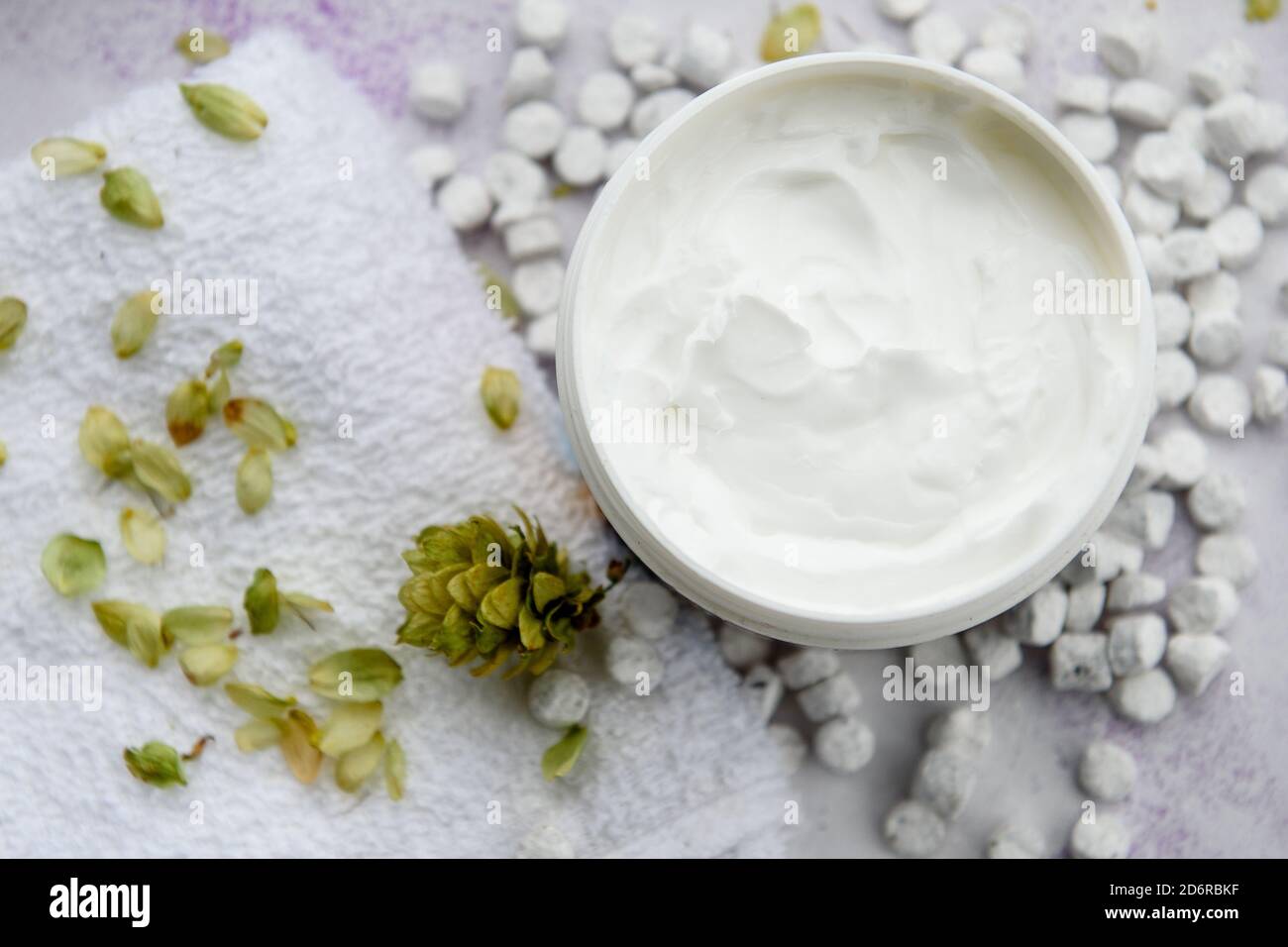Close-up of a smooth moisturizer in a plastic jar on a blue background ...