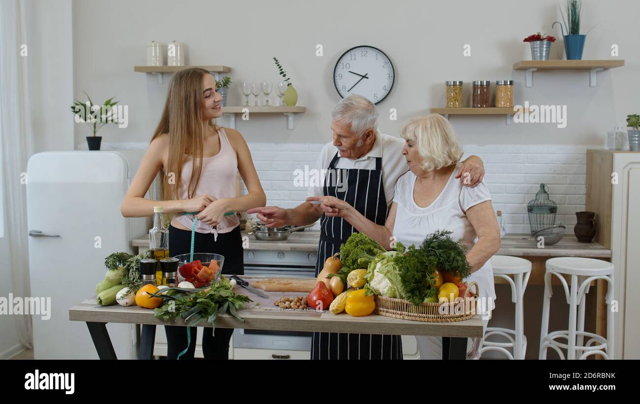 Mature grandparents couple with granddaughter in kitchen. Girl ...