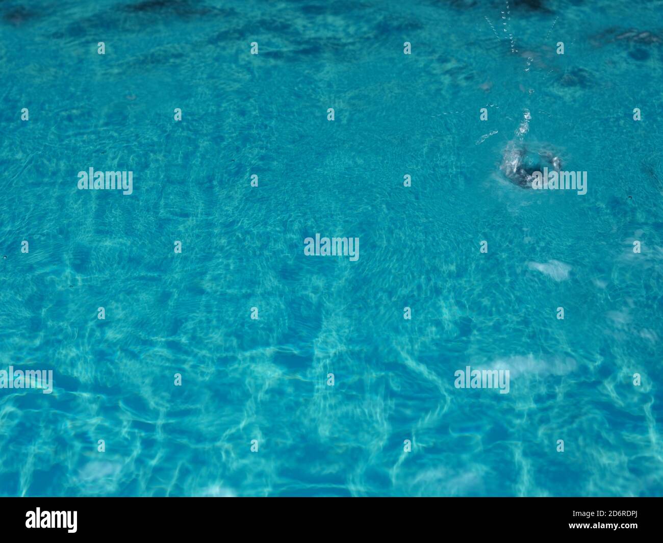 Rain drops falling blue water in pool background ripples on the surface texture, glittering ...