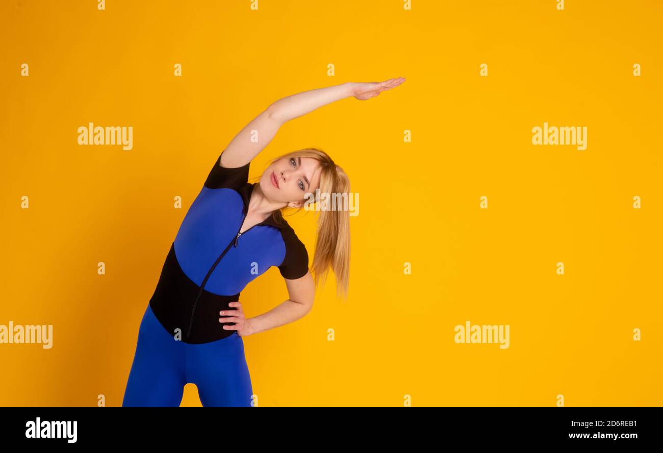Young woman in sports clothes doing side bends on white isolated ...