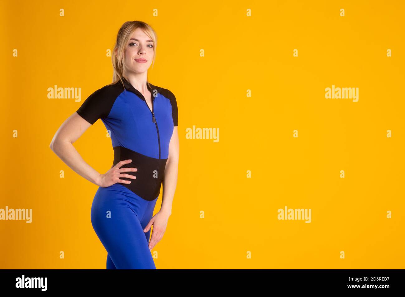 girl fitness trainer in a blue jumpsuit on a yellow background a Young ...
