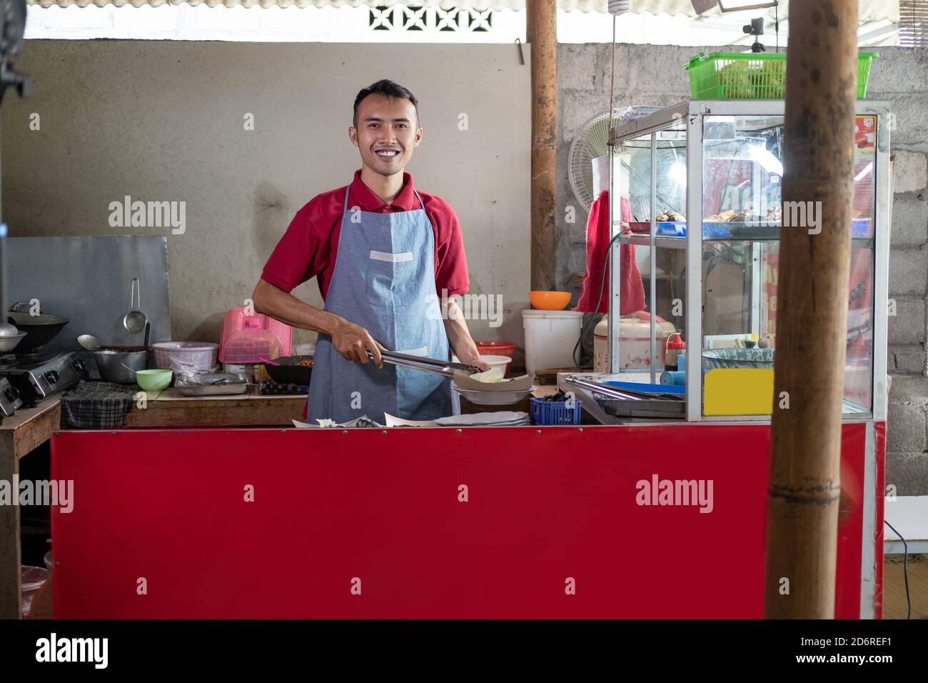 The stall waiter stands holding tongs while preparing the side dishes ...