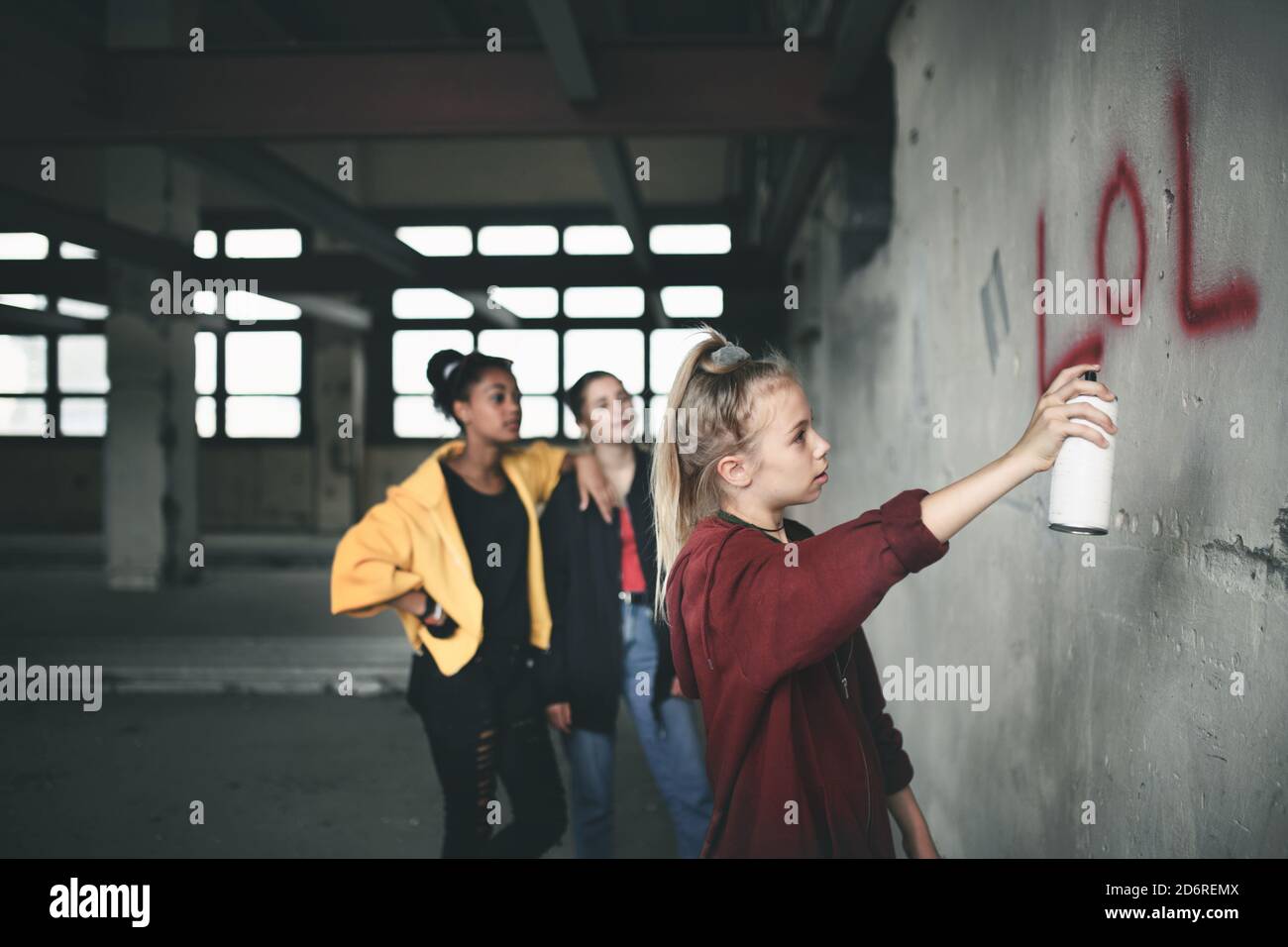 Group of teenagers girl gang indoors in abandoned building, using spray ...