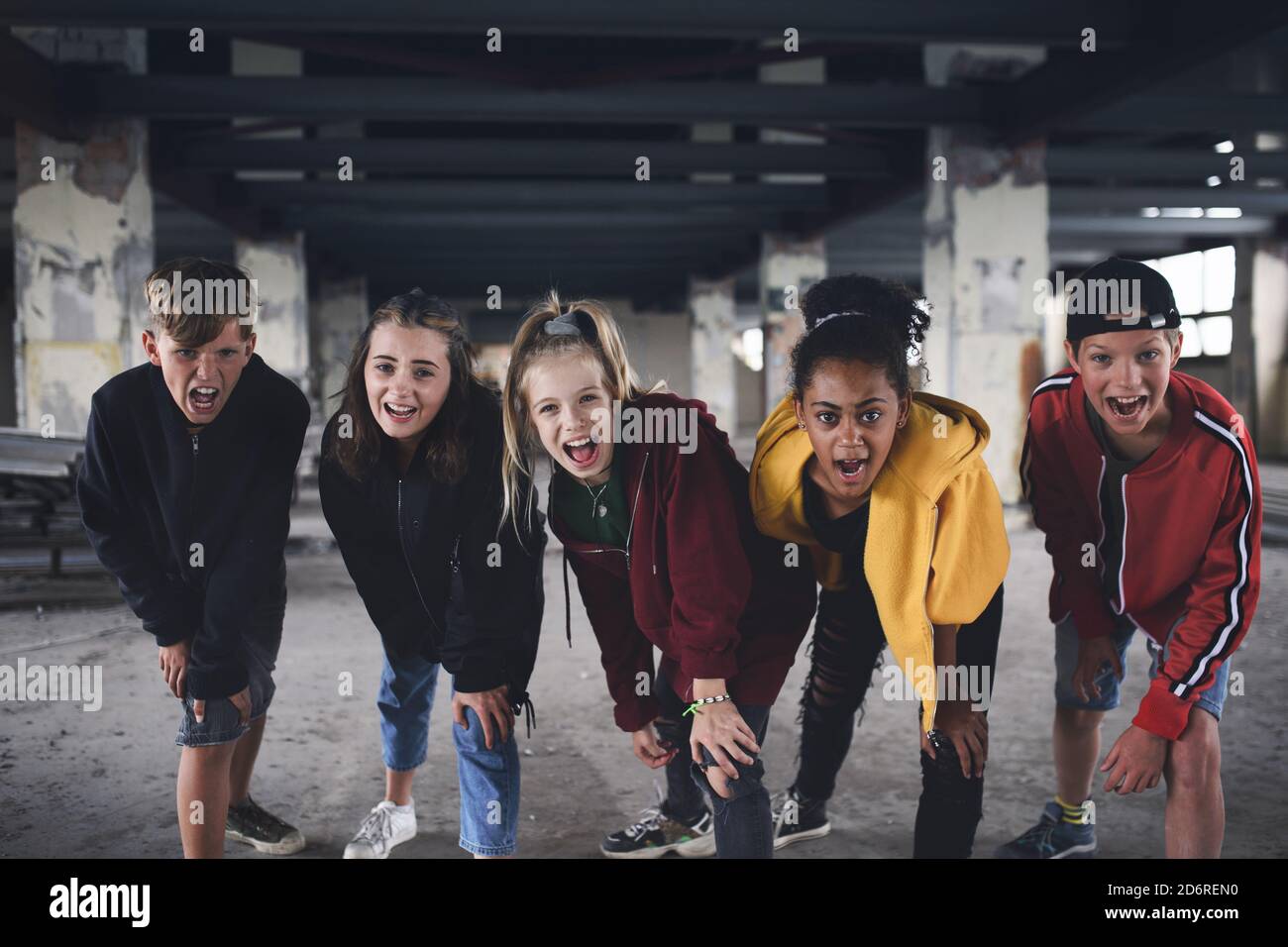 Group of teenagers gang standing indoors in abandoned building, looking ...