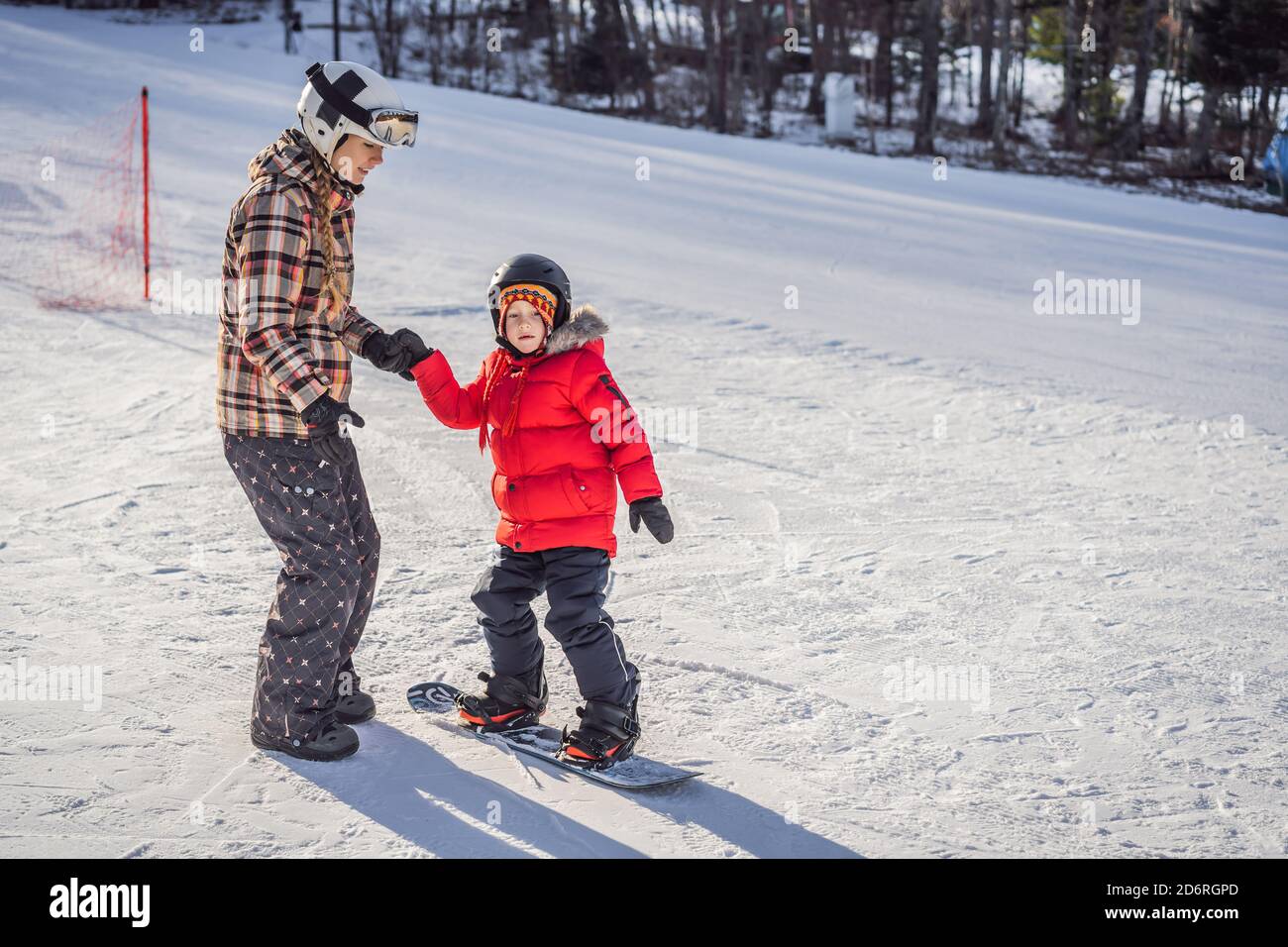 Mother teaches son snowboarding. Activities for children in winter ...