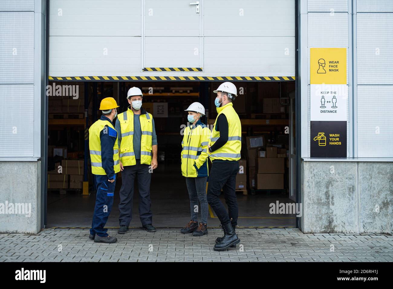 Group of workers with face mask talking in front of warehouse ...