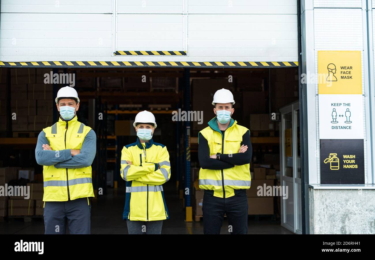 Group of workers with face mask standing in front of warehouse ...