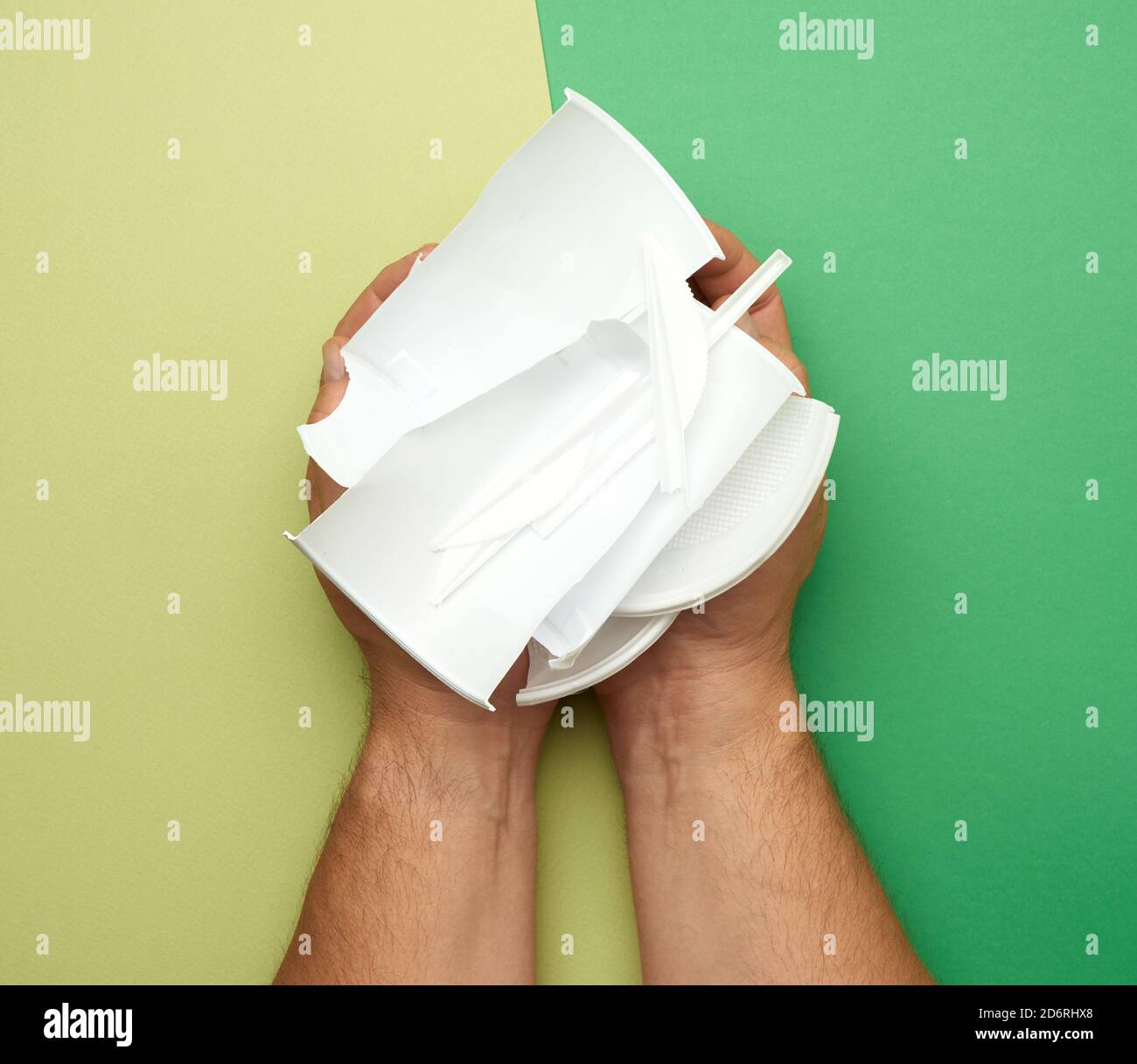 hand hold used plastic dishes, pieces of plastic on a green background ...