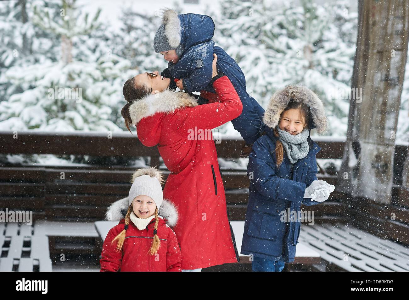 A young mother with her tree children have a fun and playing snowballs ...