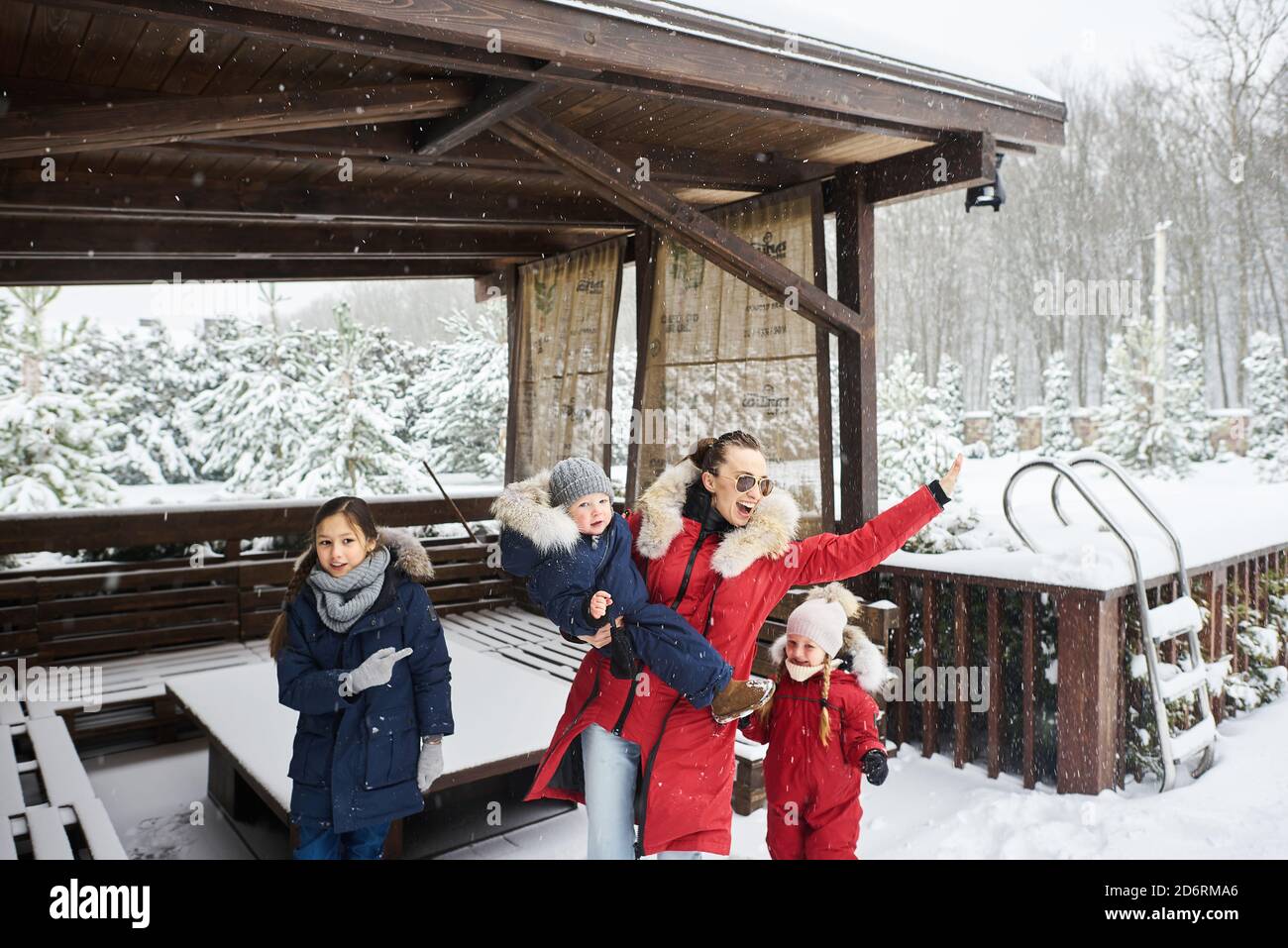A young mother with her tree children have a fun and playing snowballs ...