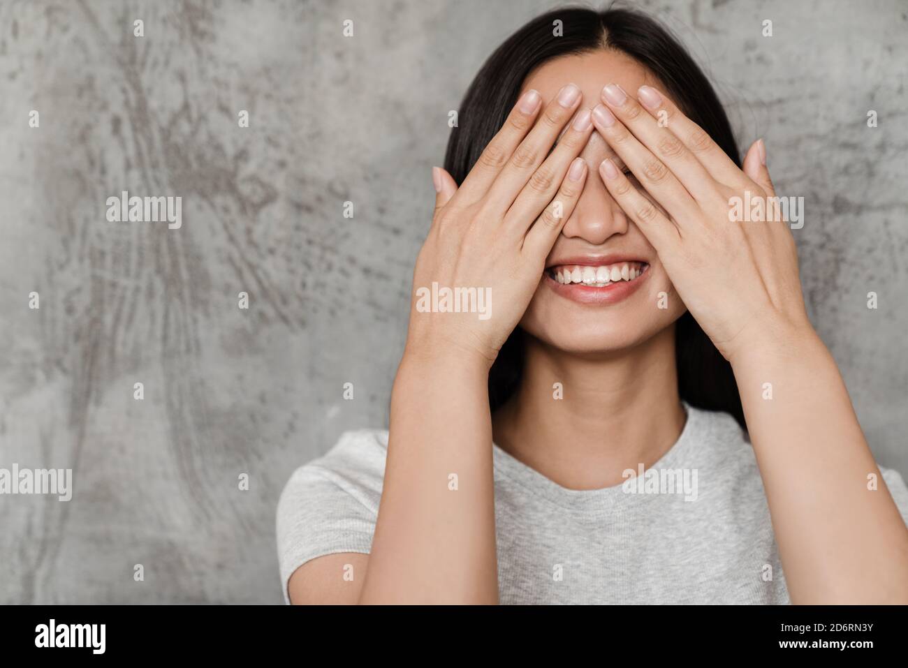 Image of joyful beautiful asian girl laughing and covering her eyes ...