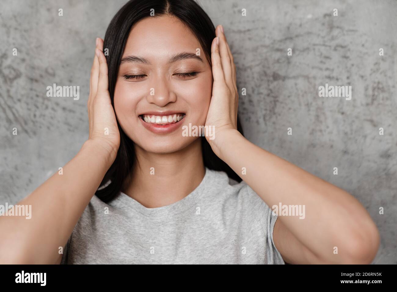 Image of joyful beautiful asian girl laughing and covering her ears ...