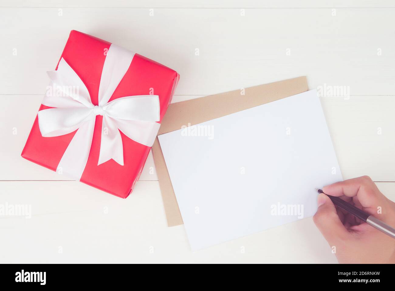 Hand of man writing letter with blank greeting card and having red gift ...