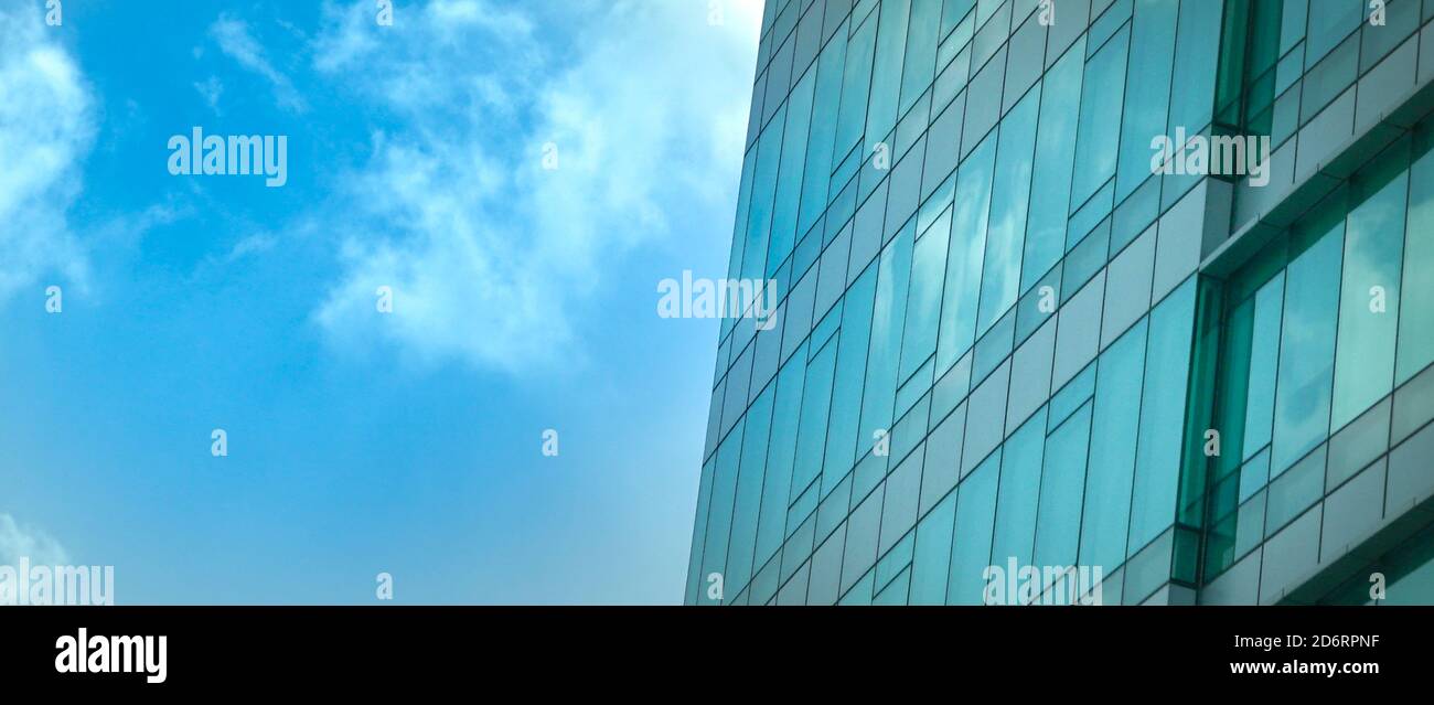 Modern high rise office building with reflection of blue sky and clouds ...