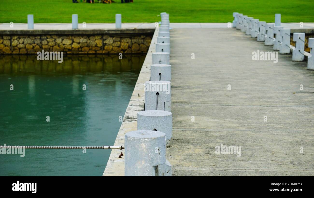 Concrete pedestrian walkway protection near a lake in a park. White ...