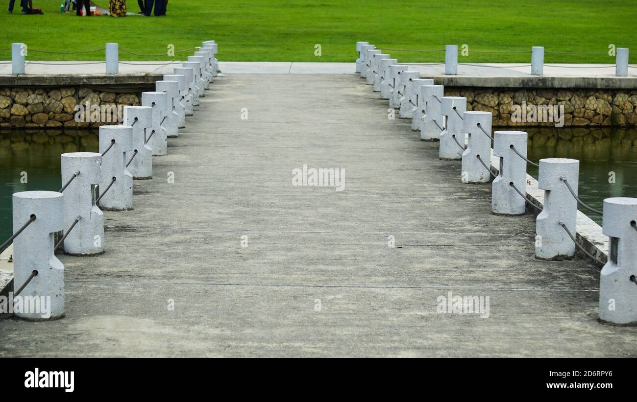 Concrete pedestrian walkway protection near a lake in a park. White ...