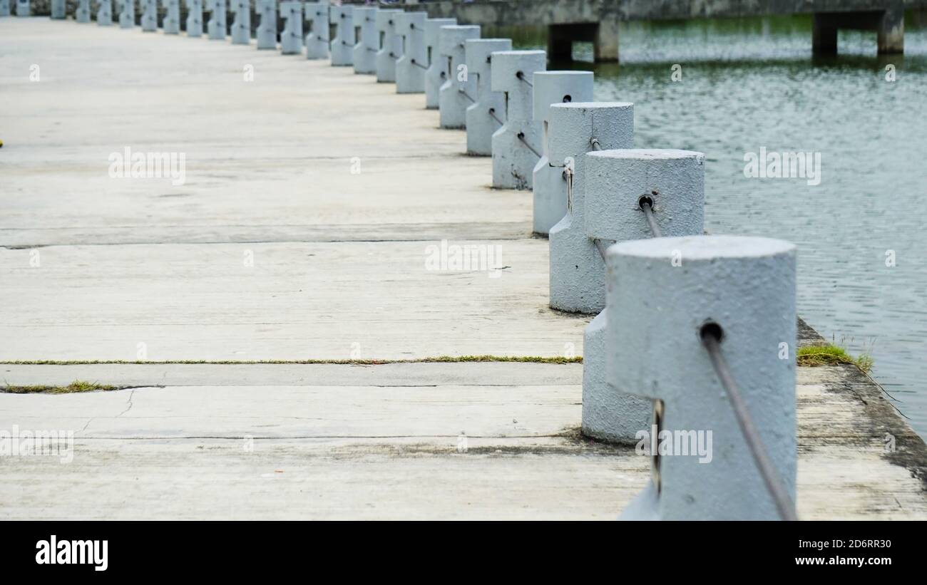 Concrete pedestrian walkway protection near a lake in a park. White ...