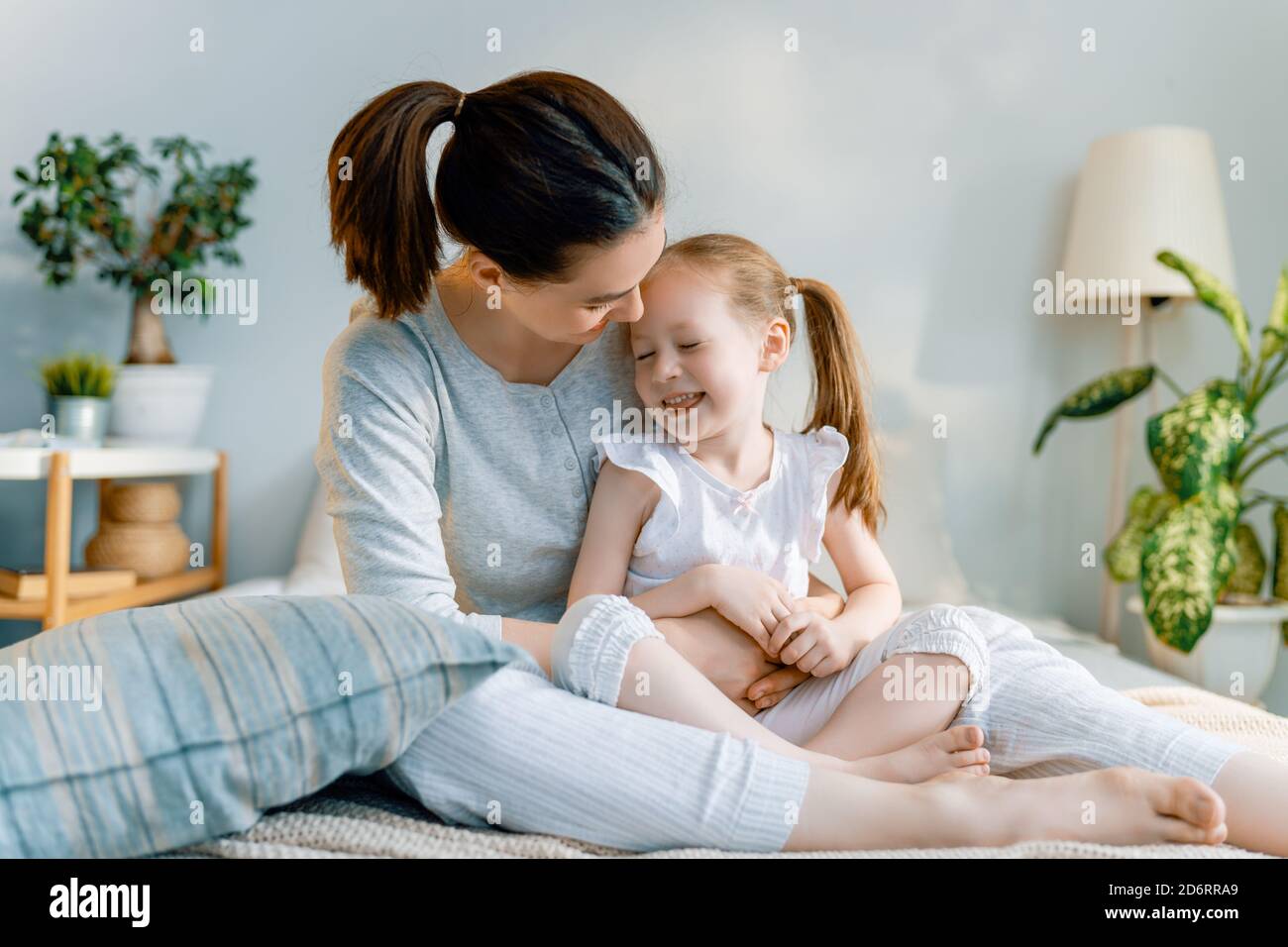 A nice baby girl and her mother enjoy sunny morning. Good time at home ...