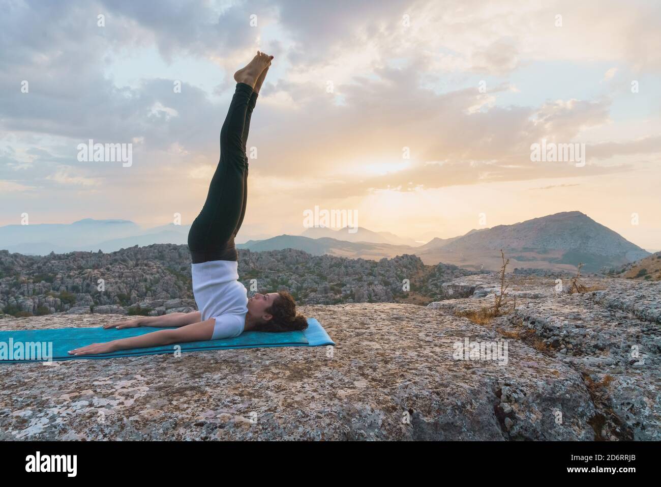 Full body side view of slim female in activewear using yoga wheel while ...