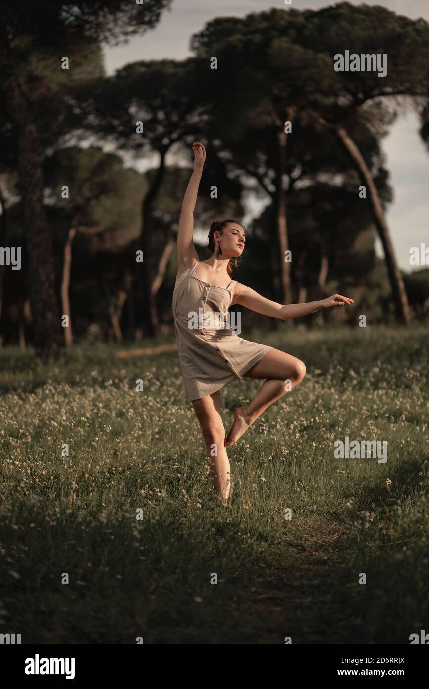 Tranquil female ballet dancer balancing barefoot on meadow in park in ...