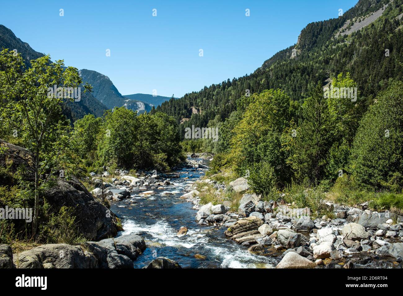 Long narrow waterfall of mountain river flowing over big stones between ...