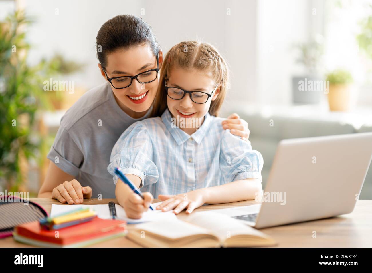 Back to school. Happy child and adult are sitting at desk. Girl doing ...