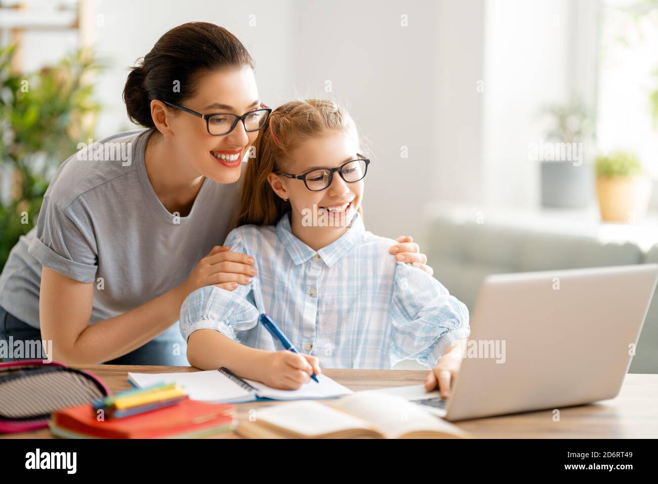 Back to school. Happy child and adult are sitting at desk. Girl doing ...