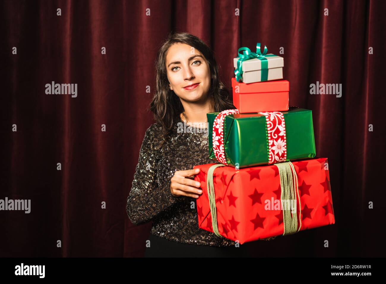 Charming female wearing fancy shiny dress standing in studio with pile ...