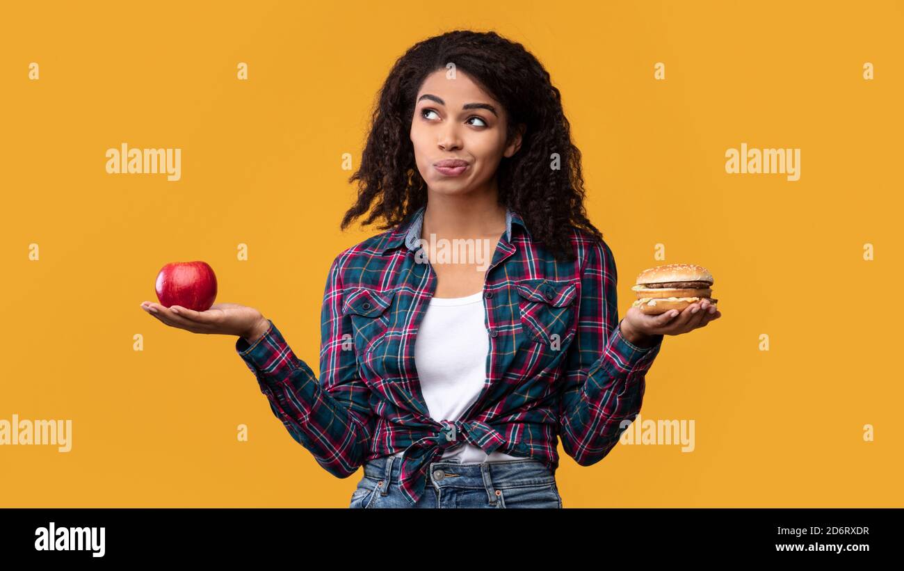 Hungry Black Lady Holding Burger And Apple Fruit Stock Photo - Alamy