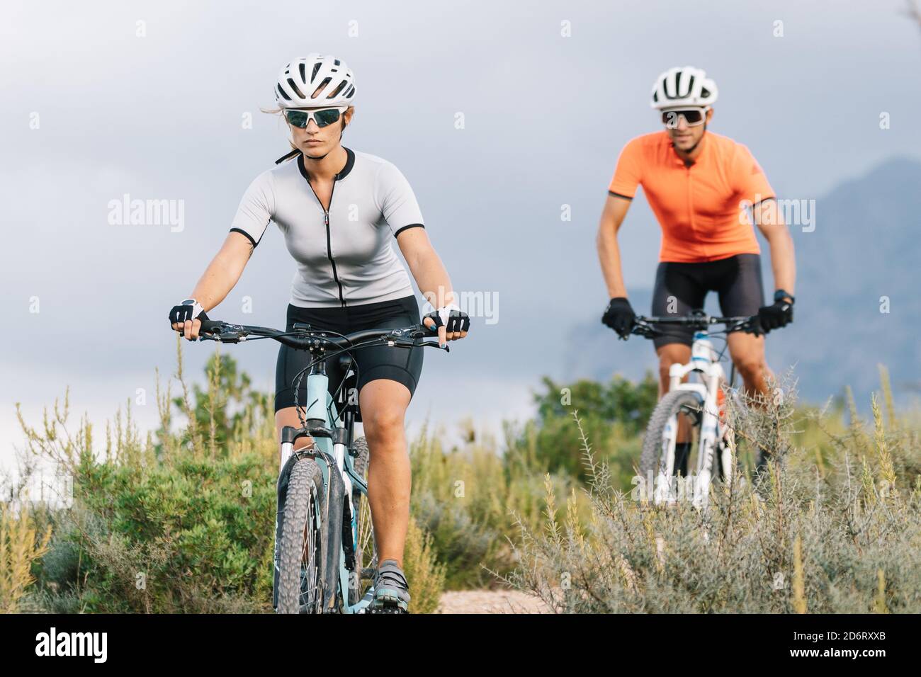 Serious professional bicyclists in helmets and sunglasses riding uphill ...