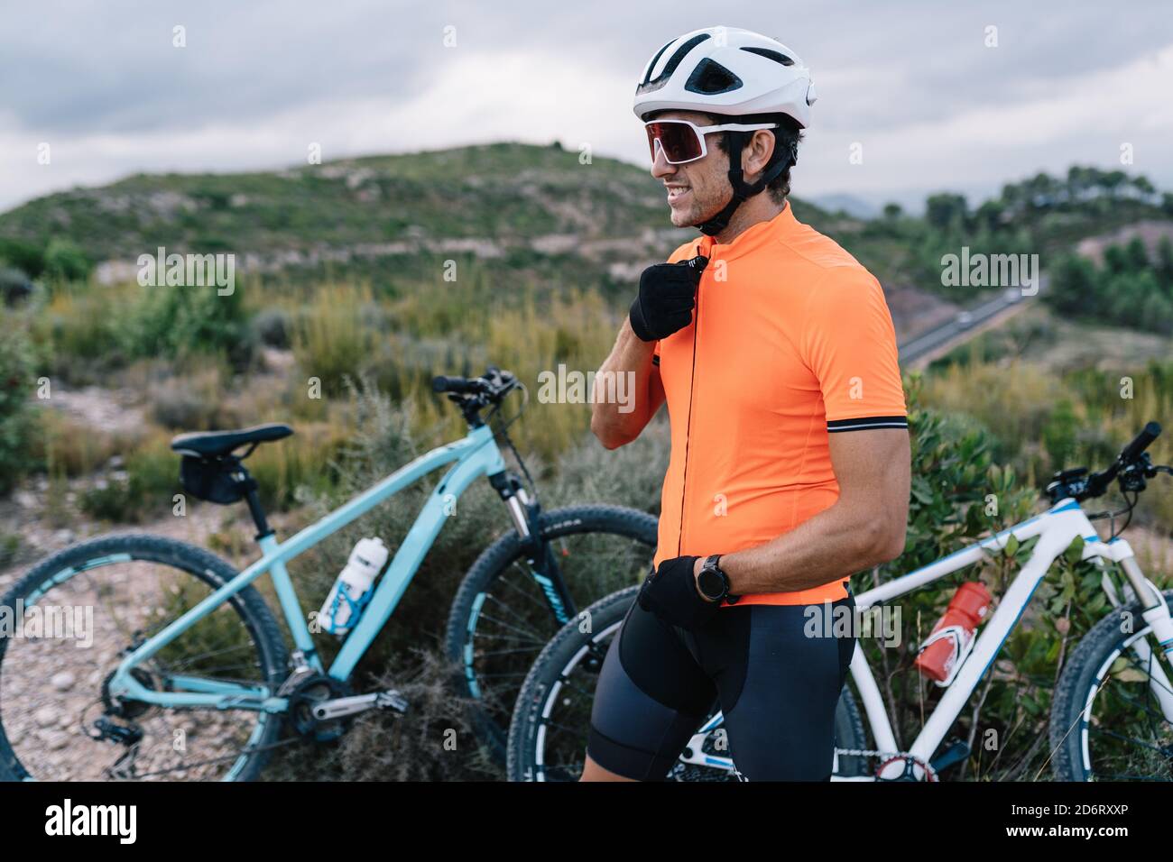 Side view of handsome male bicyclist standing in mountainous area near ...