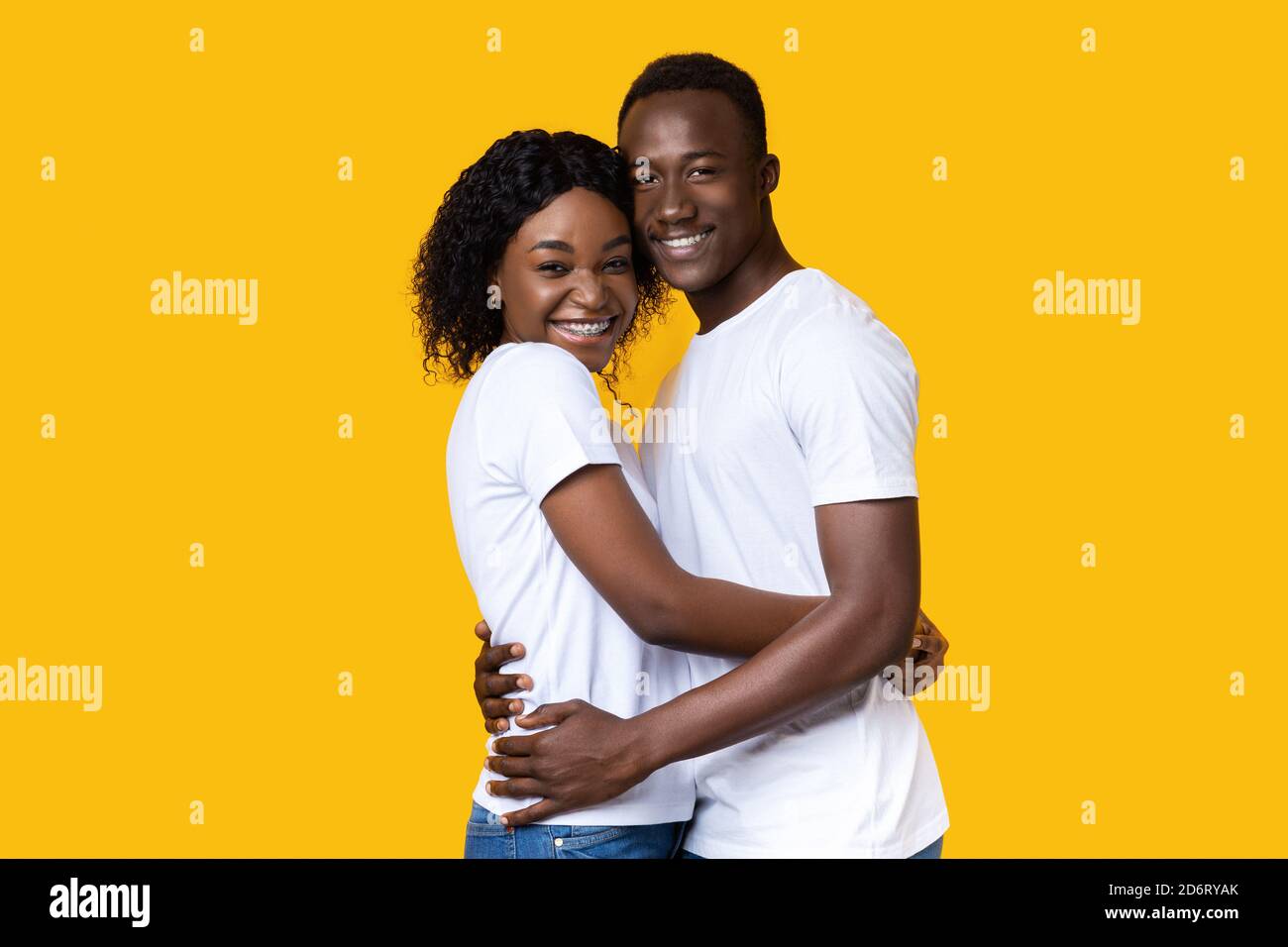 Happy black couple in love embracing on yellow studio background Stock ...