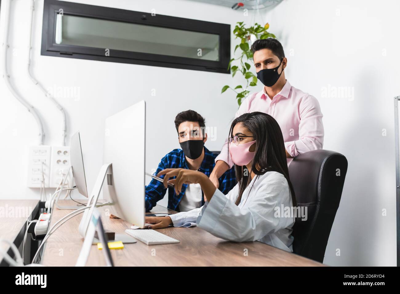 Anonymous entrepreneur in mask showing project on desktop computer ...