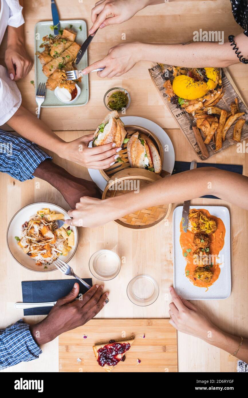 Top view crop multiethnic friends gathering at table in modern ...