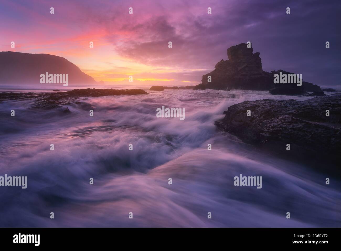 Rocky formations on rippled ocean with fast water flow under cloudy sky ...