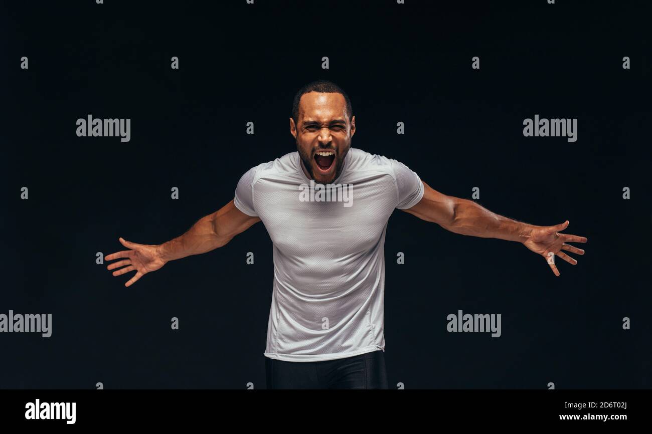 fitness man shouting with stretched arms on black background ...