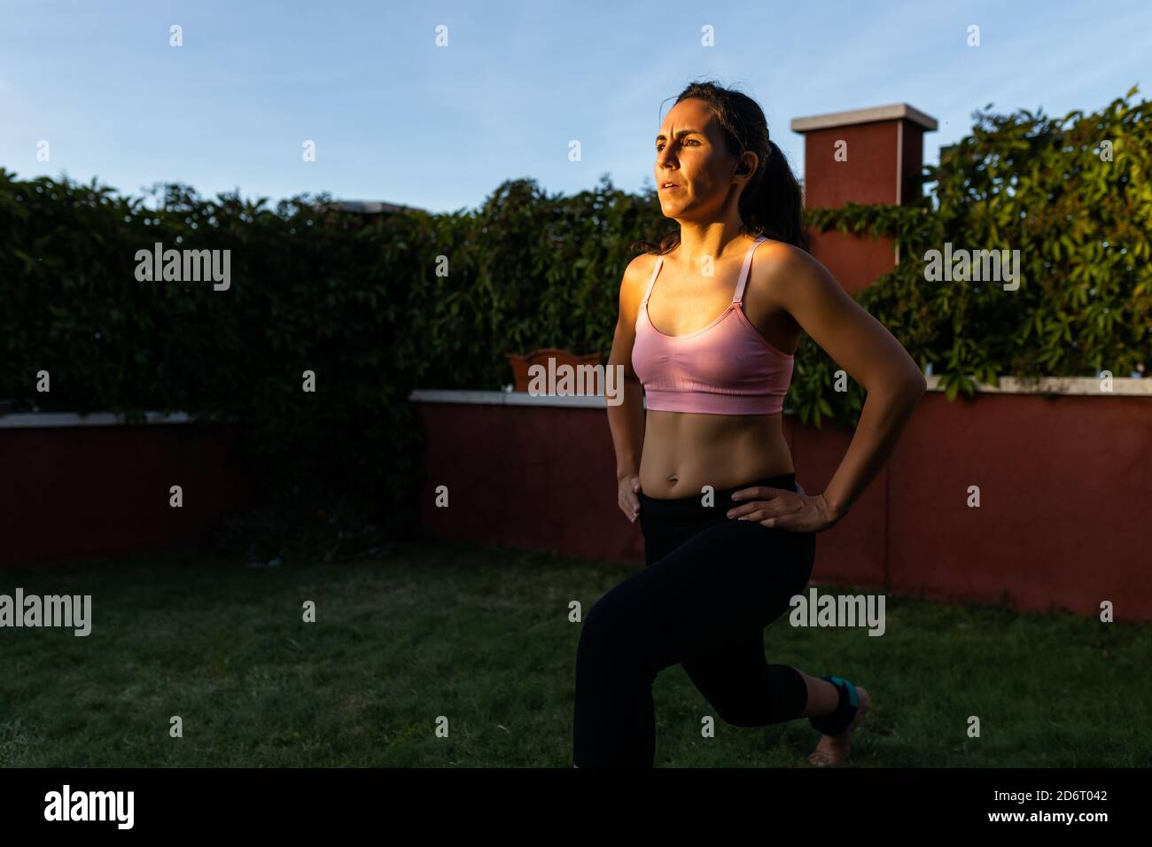 Fit female athlete in sportswear using laptop and doing lunges while ...