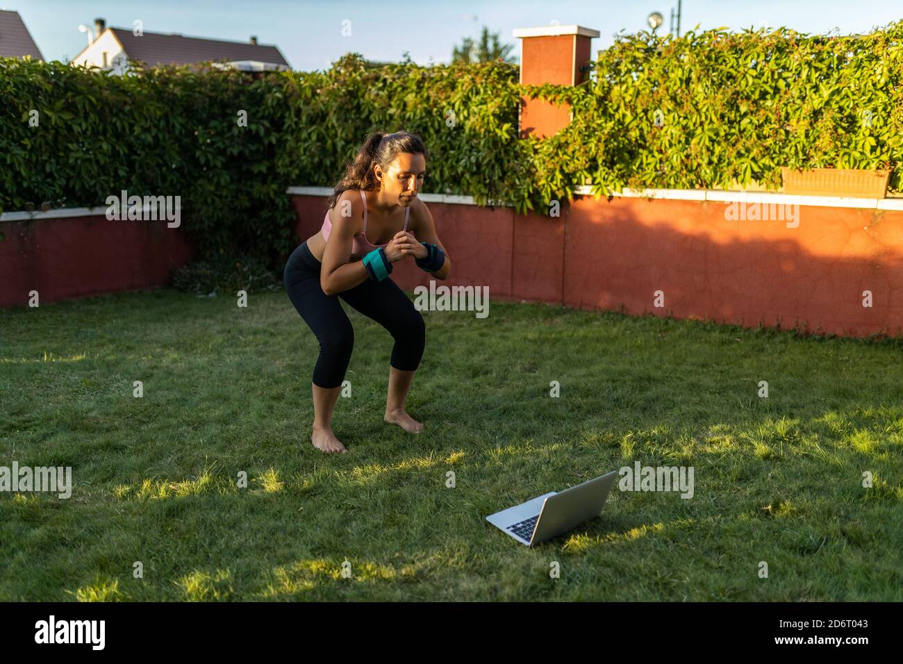 Side view of fit female athlete in sportswear using laptop and doing ...