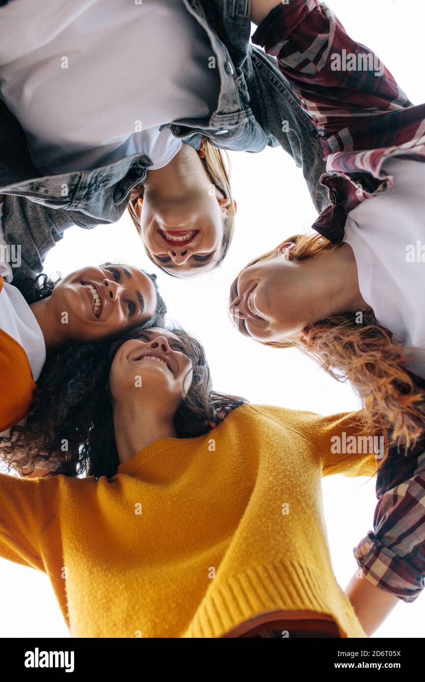 Group of female friends in a huddle. Low angle view of cheerful females ...
