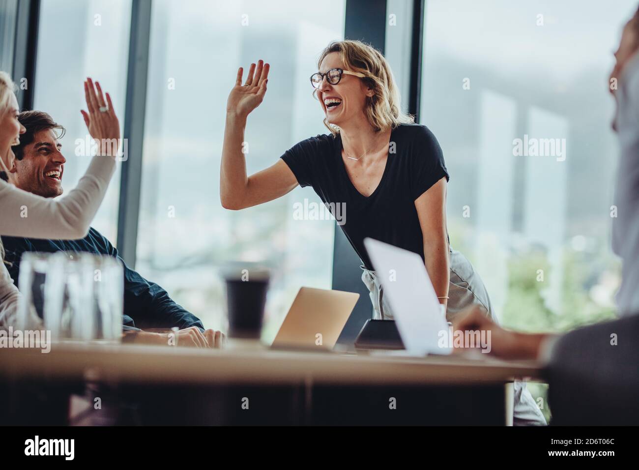 Smiling woman giving a high five to a female colleague in meeting ...