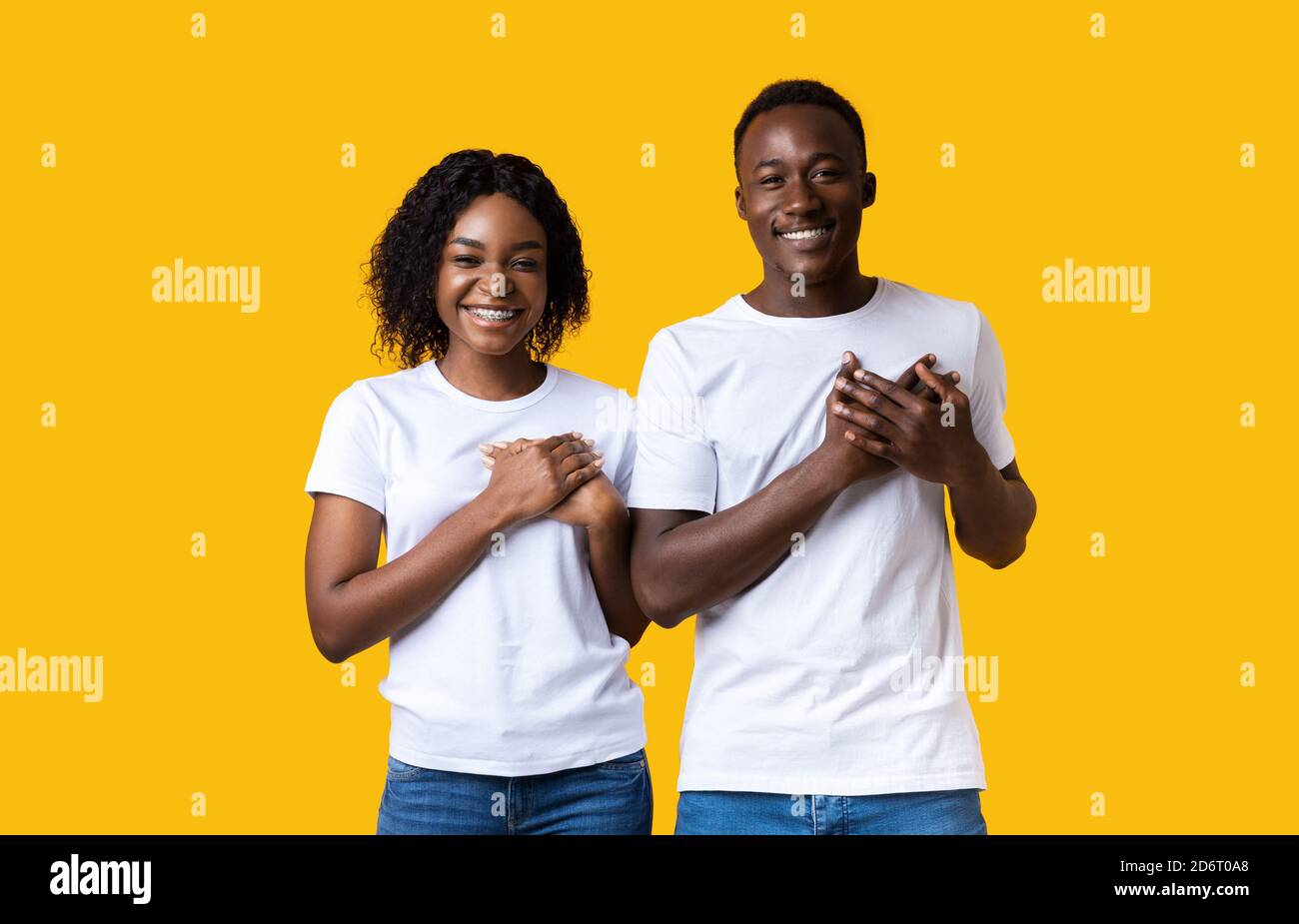 Kind woman and man keeping both palms on chest Stock Photo - Alamy