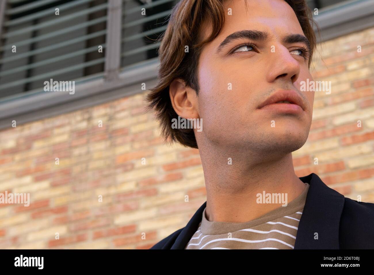 From below young reflective trendy male looking away standing on shabby ...