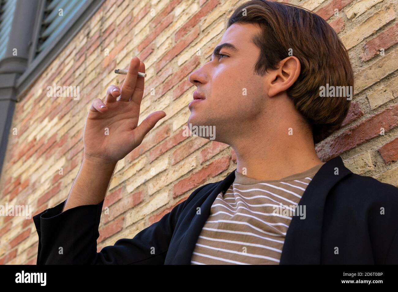 Side view of crop young trendy concentrated male smoking cigarette on ...