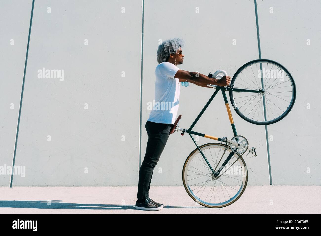 Black and afro man taking the bike and carrying it on a gray background ...