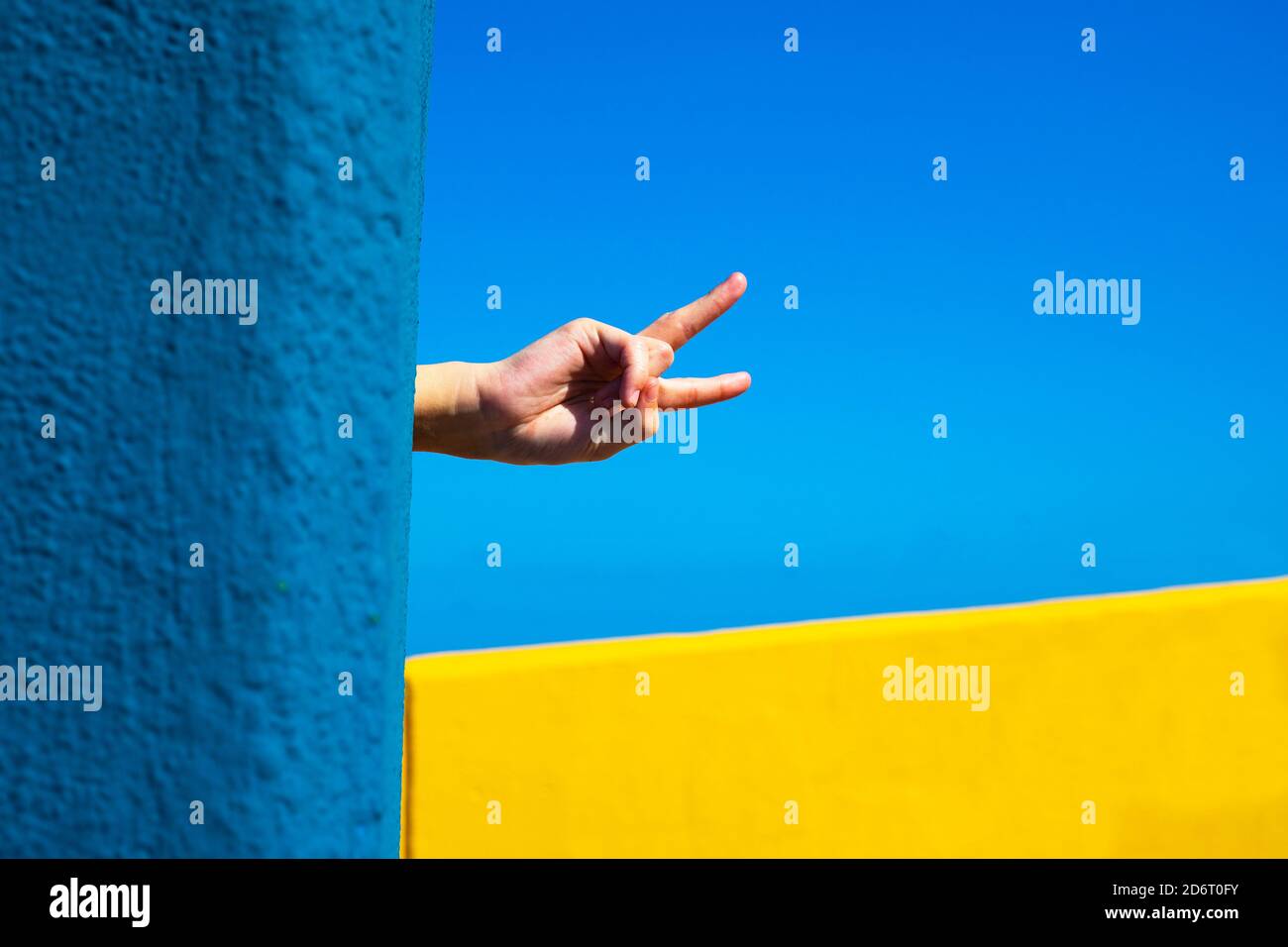 Hand on a blue and yellow background making the victory sign. Victory ...