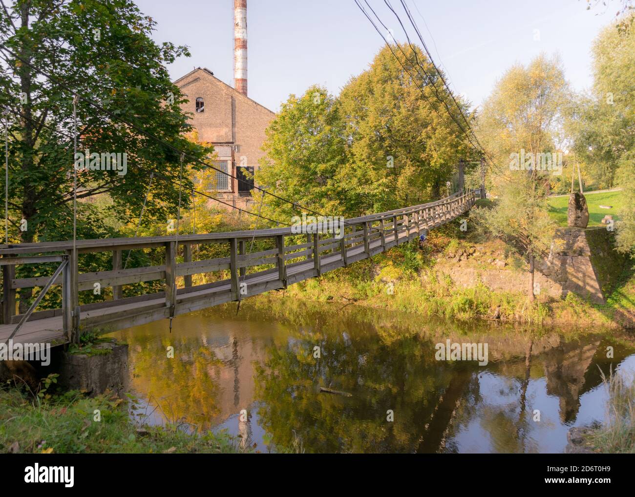 picture with wooden bridge over the river, trees and shrubs in the ...