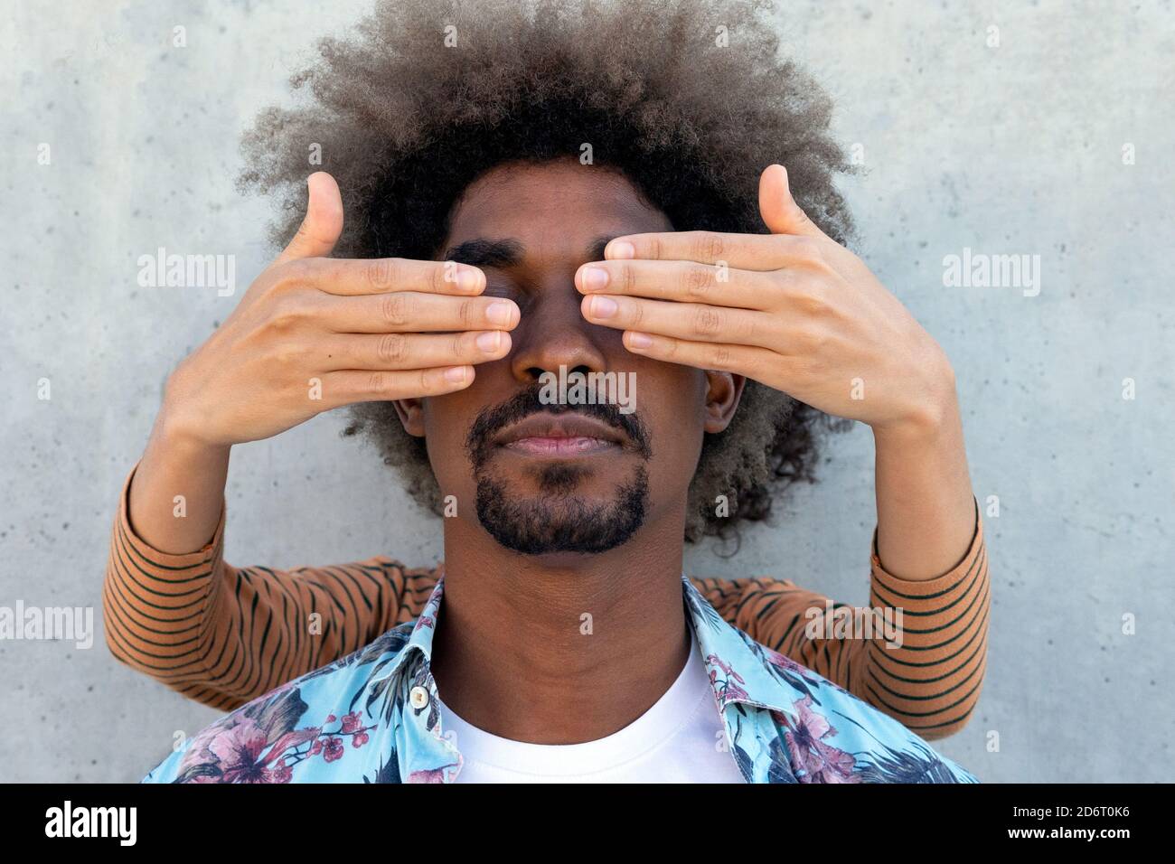Anonymous friend covering eyes of stylish ethnic male with Afro ...